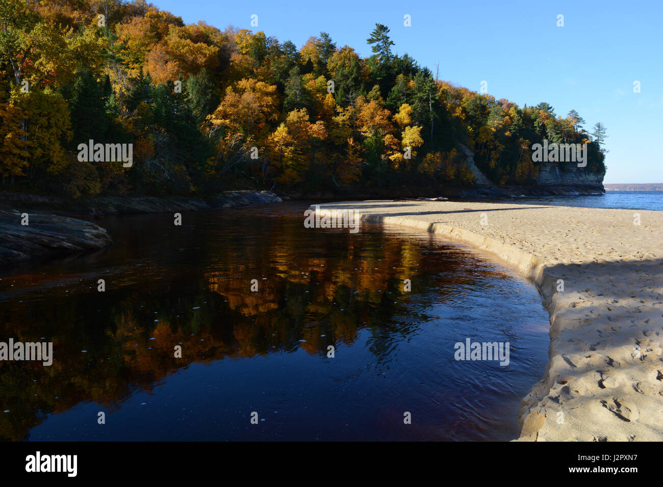 Fall color reflects into a body of water at Miners Beach along the ...