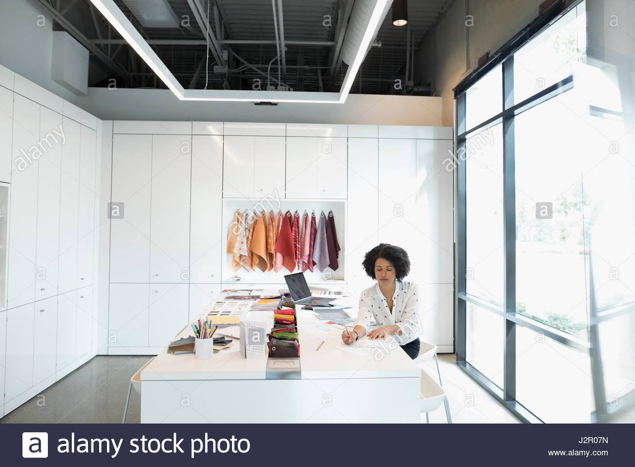 Female designer working, drafting plans in conference room Stock Photo ...
