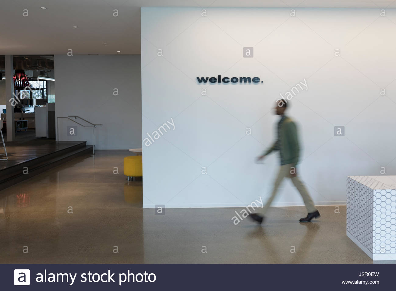 Businessman walking past welcome sign in office lobby Stock Photo - Alamy