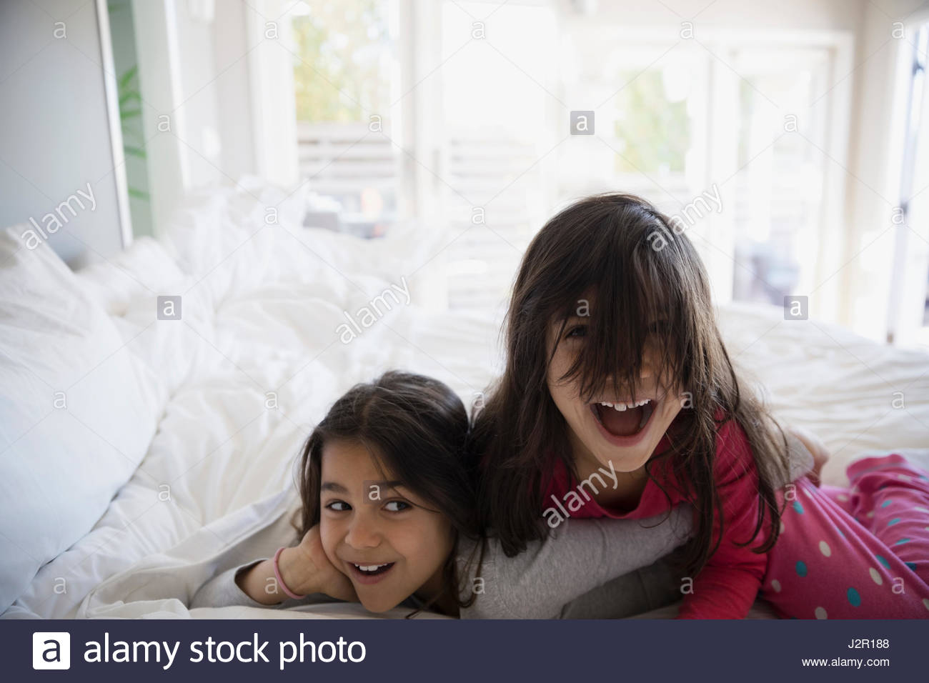 Portrait playful sisters laughing on bed Stock Photo - Alamy