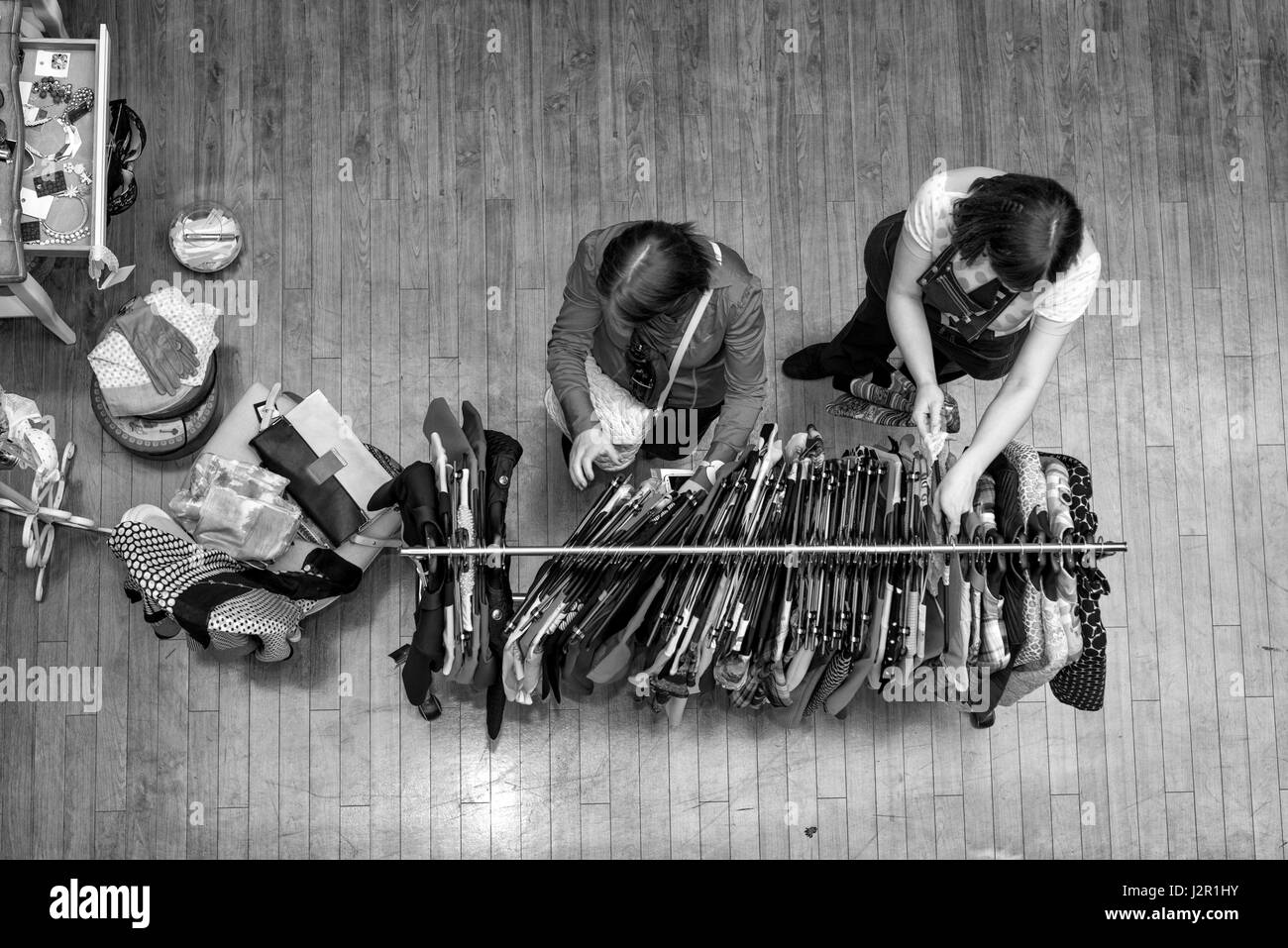 Two women in the shop chooses colored clothes from traders offer Stock ...