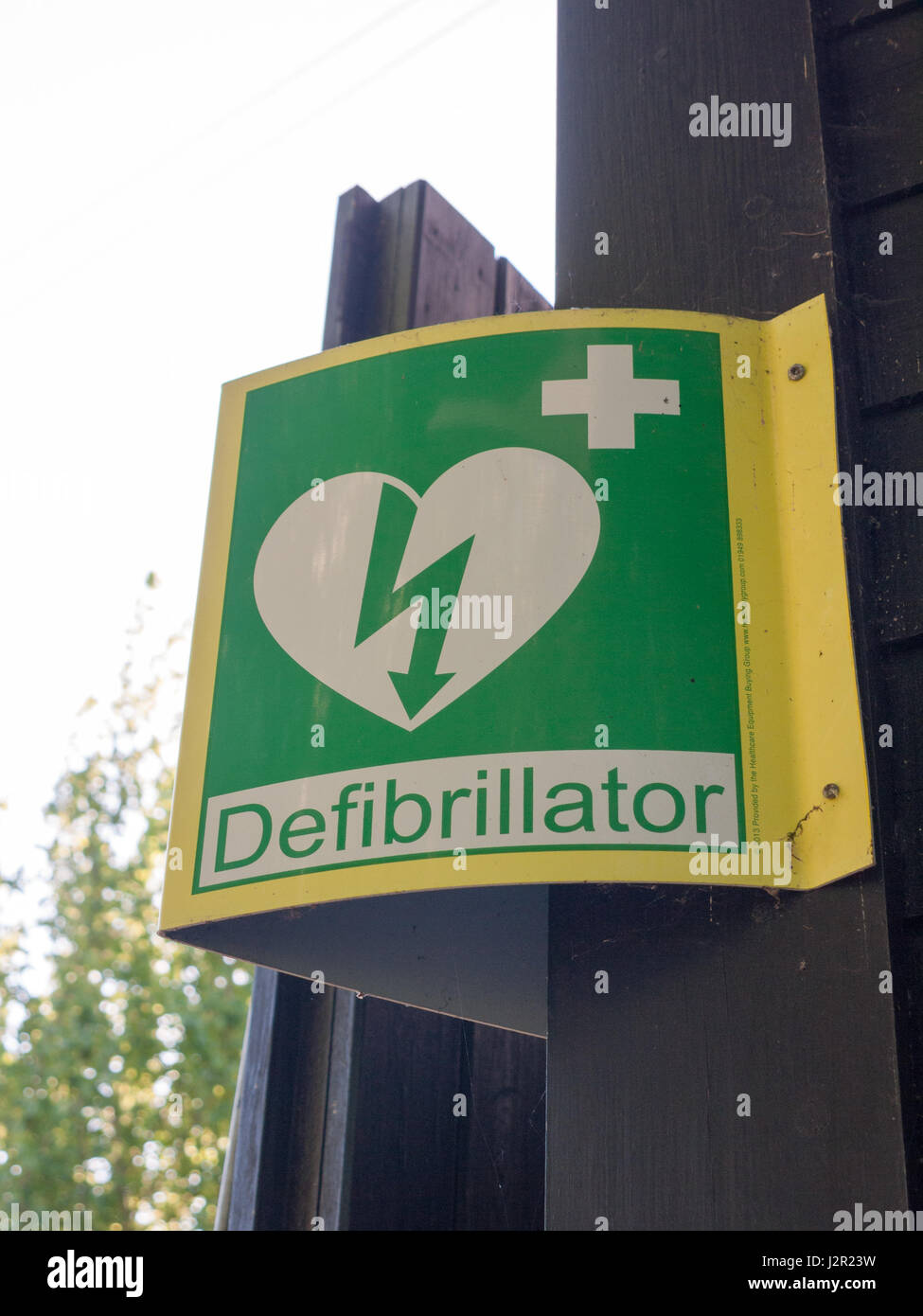 a sign outside indicating a nearby defibrillator yellow and green ...