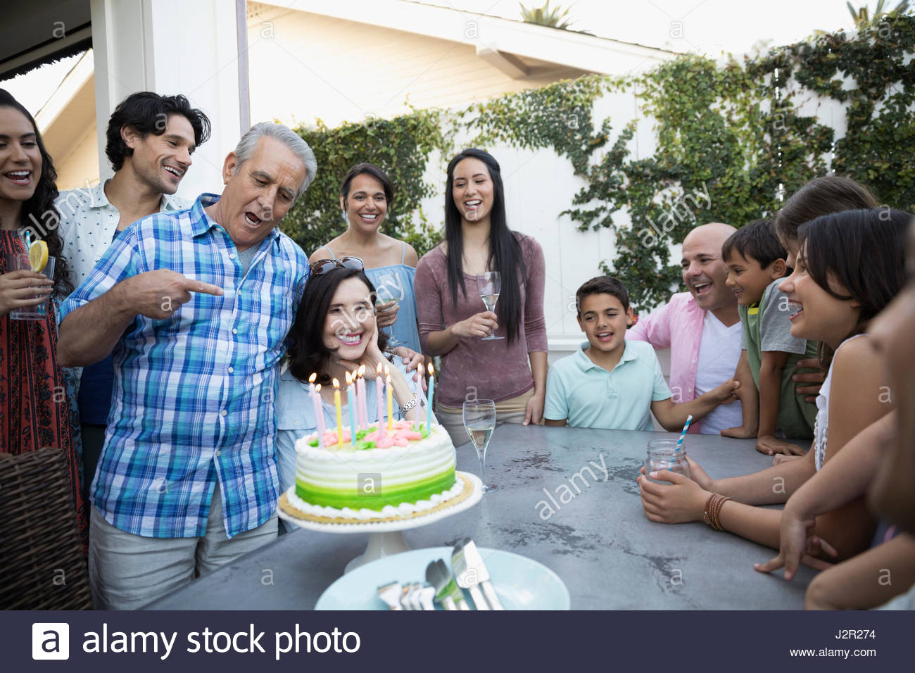 Multi-generation family celebrating birthday with cake and candles on ...