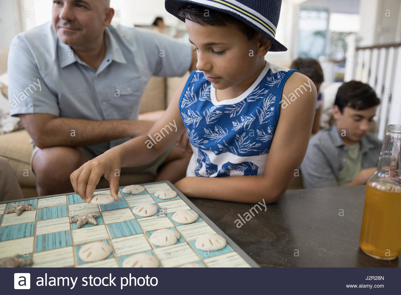 Boy playing checkers with seashells in beach house Stock Photo - Alamy