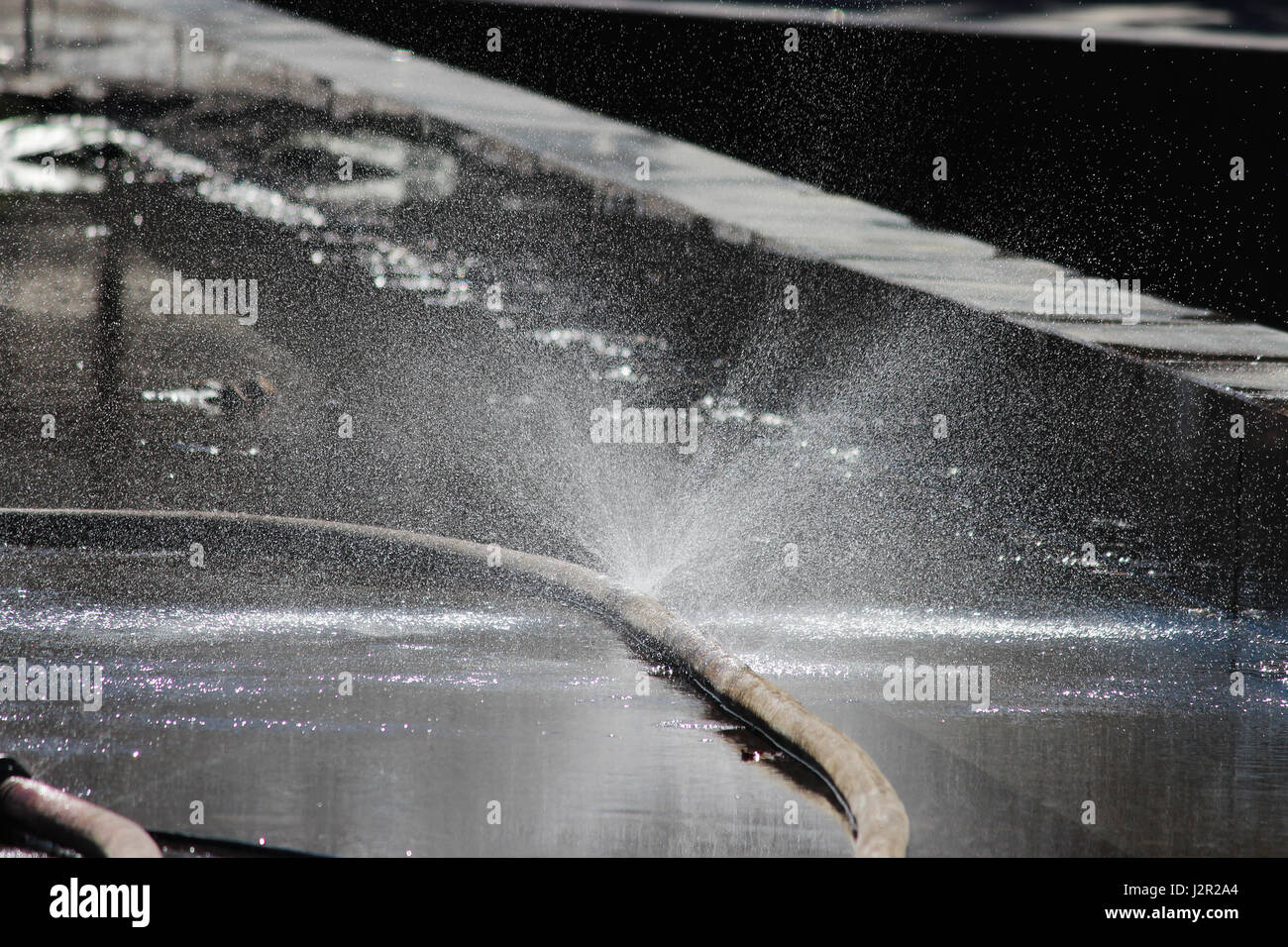 Thin streams of water from the hose in front of the sunlight in the ...