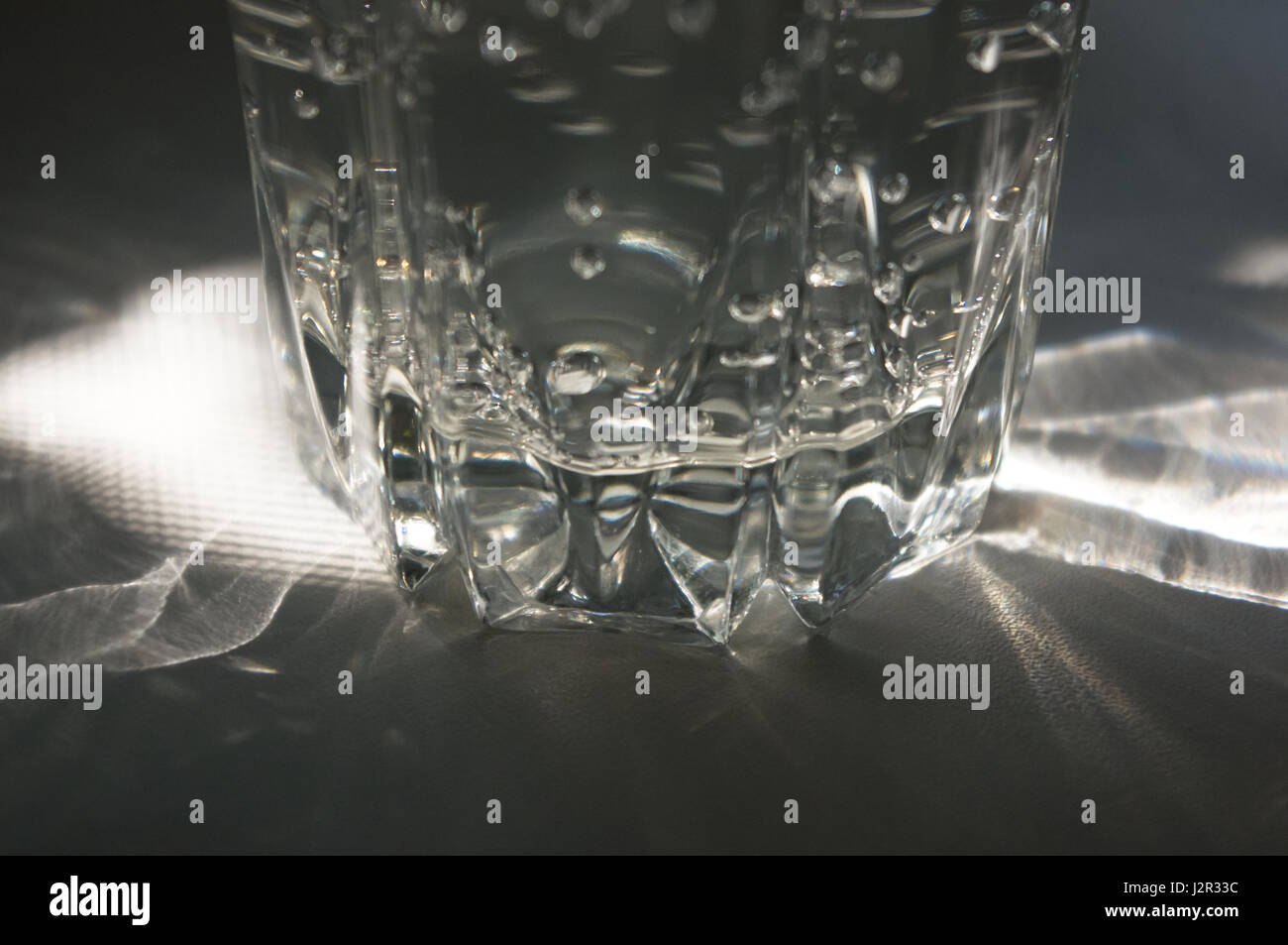 transparent faceted glass with bubbly water in the sun refracted light ...