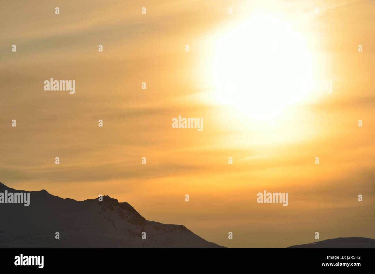 huge golden sunset over snowy mountain peak background Stock Photo - Alamy