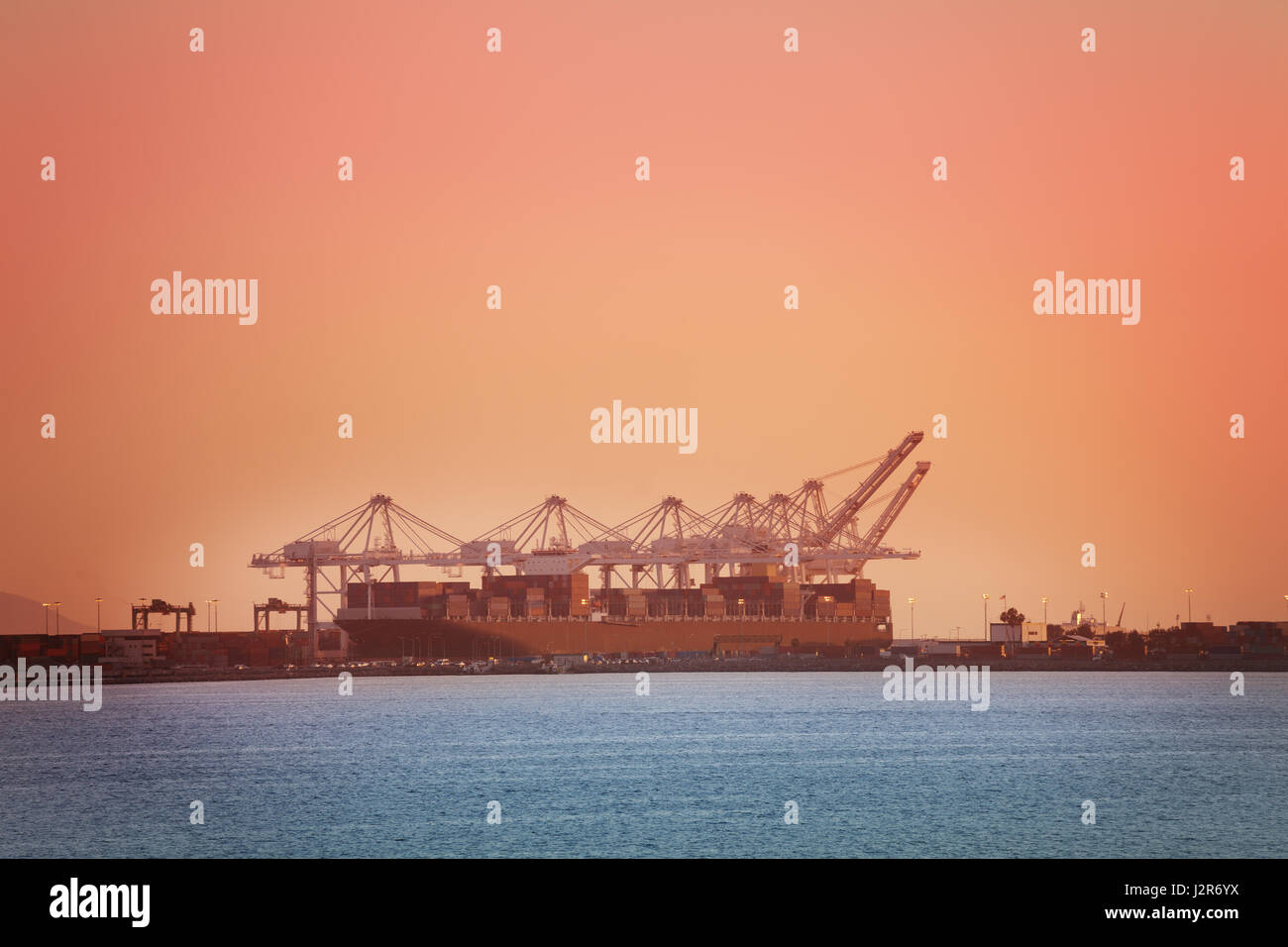 Crane bridge loading containers on barge at Long Beach shipping port at ...