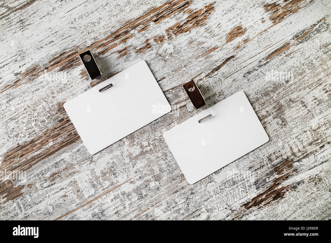Two blank badges on vintage wooden background. Blank plastic id cards ...