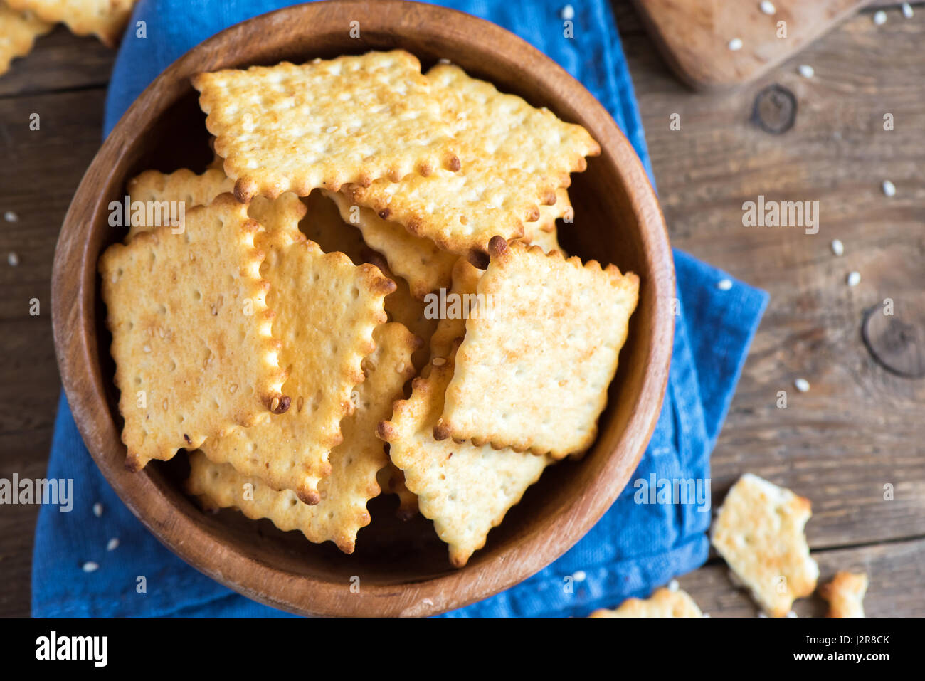 Homemade thin crispy cheesy crackers with sesame seeds in rustic wooden ...