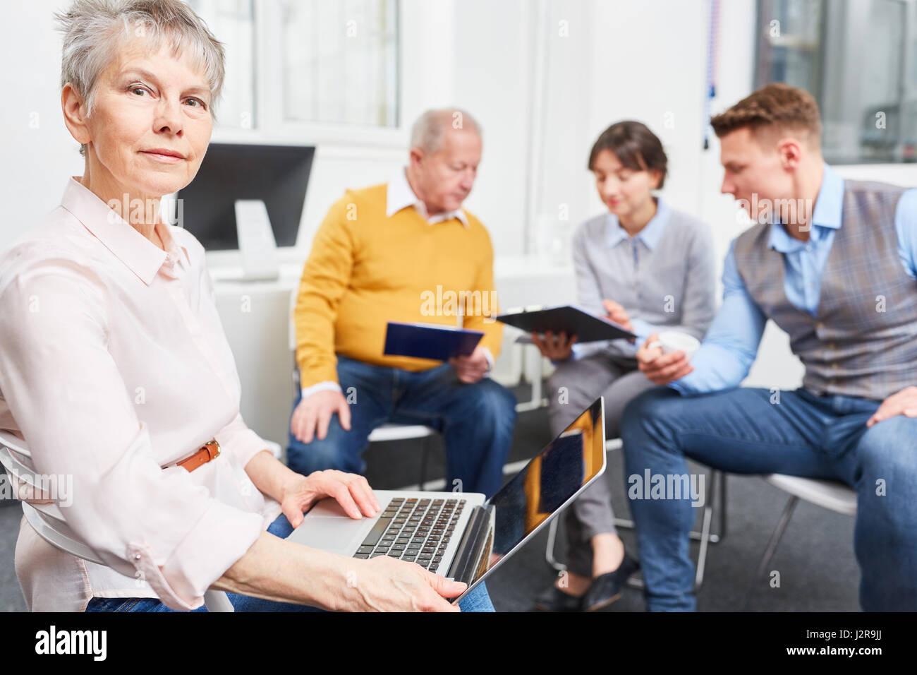 Senior citizen holding laptop in e-learning workshop Stock Photo - Alamy