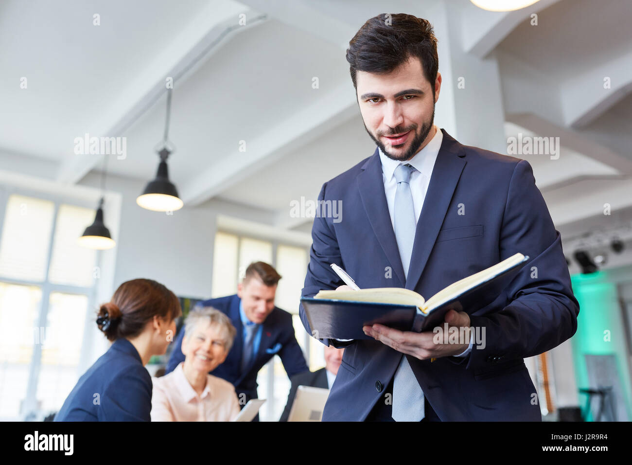 Start-up man as manager and controller with business team in the back ...