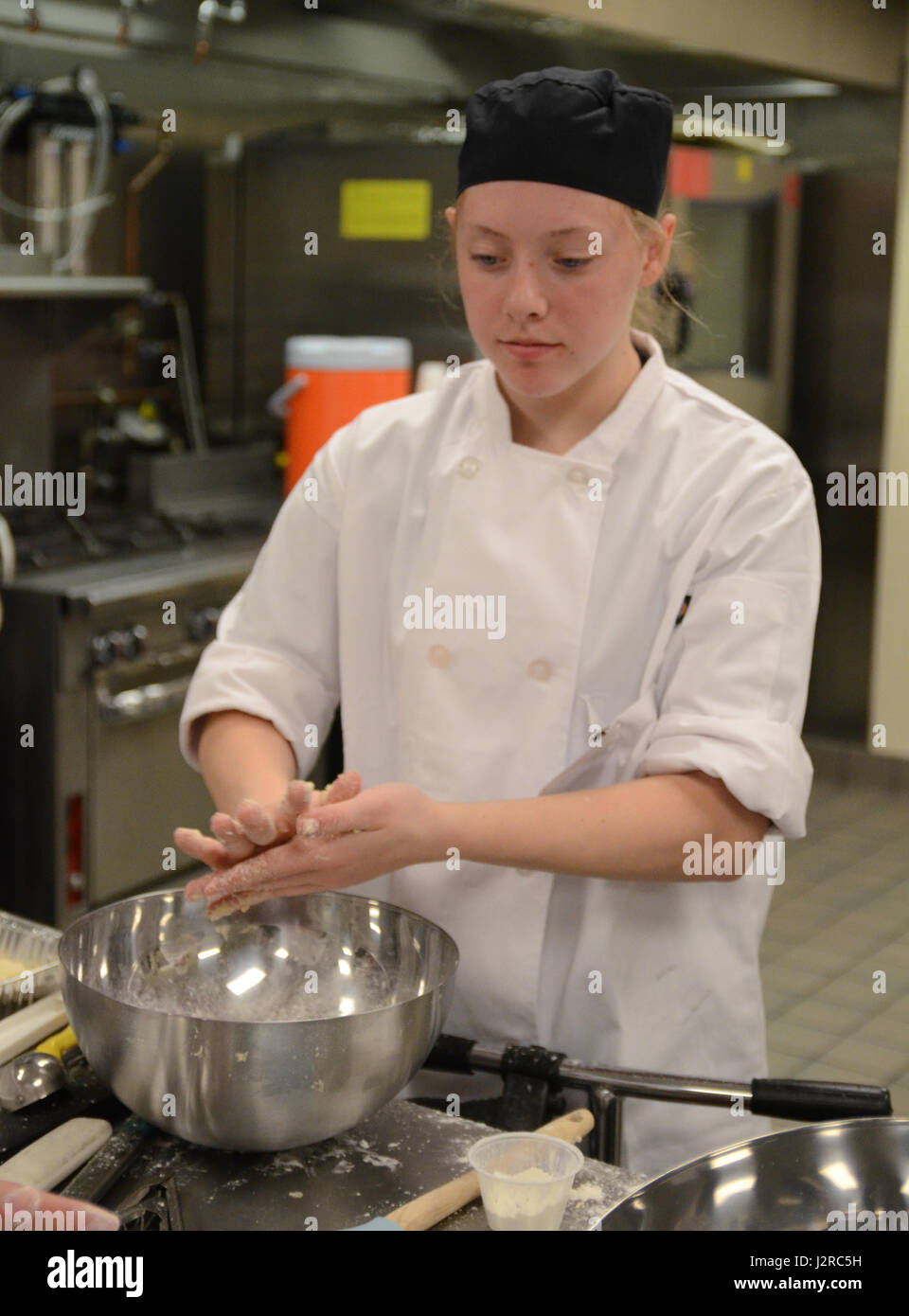 A high school student kneads some dough to make scones during the ...