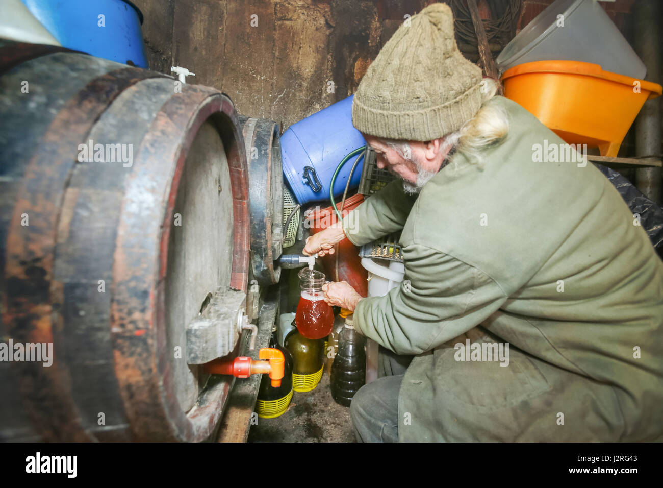A man pouring homemade wine from a barrel into the pitcher Stock Photo ...