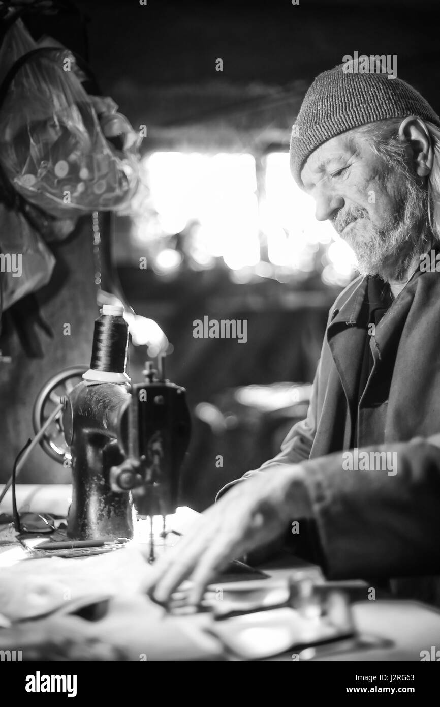 A senior adult man sewing a piece of cloth on a sewing machine Stock ...