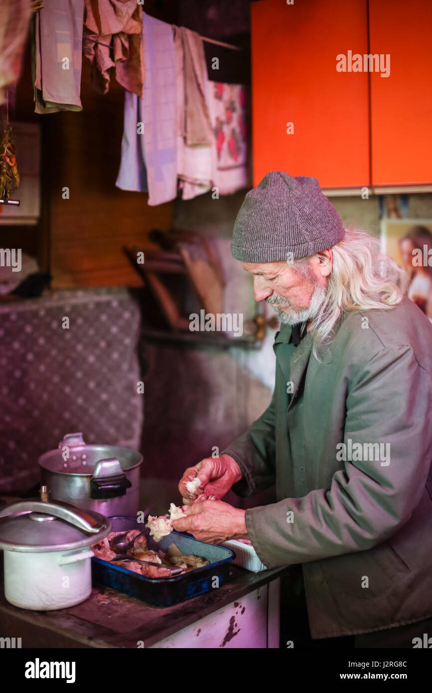 An old man eating pork meat after cooking it Stock Photo - Alamy