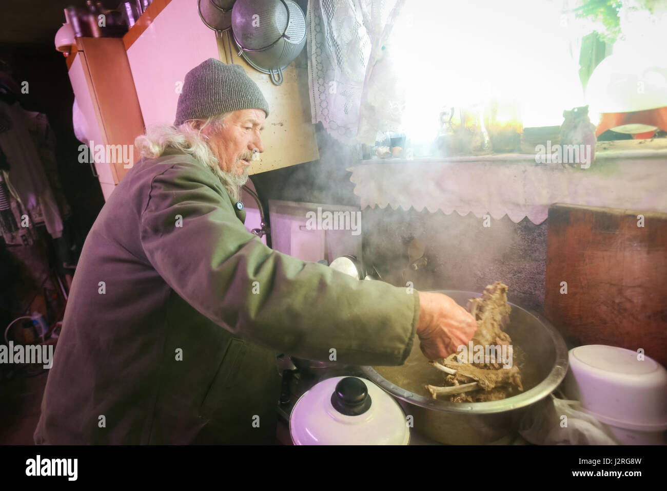 An old man boiling pork meat on the stove Stock Photo - Alamy