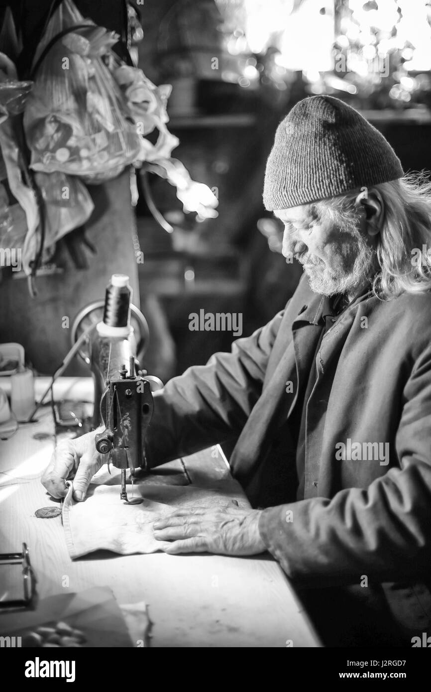 A senior adult man sewing a piece of cloth on a sewing machine Stock ...