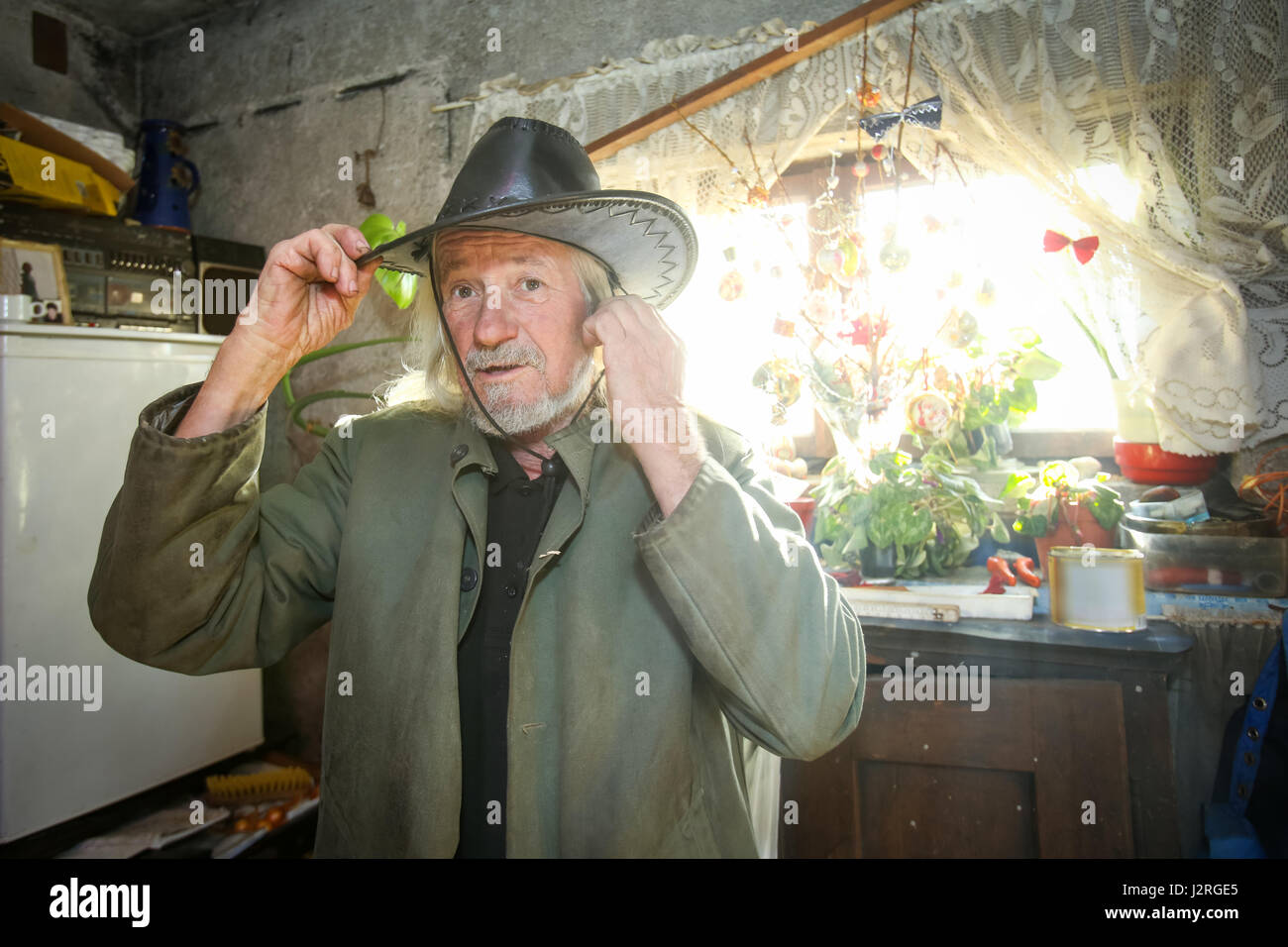 A front view of an old man putting a hat on his head Stock Photo - Alamy