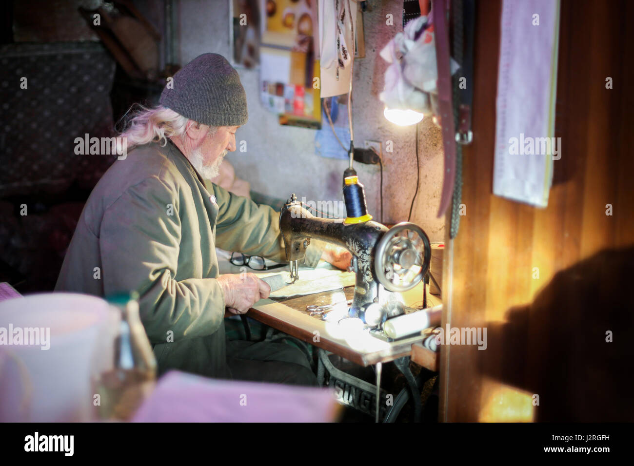 A senior adult man sewing a piece of cloth on a sewing machine Stock ...