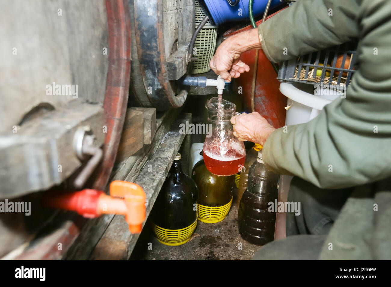 A man pouring homemade wine from a barrel into the pitcher Stock Photo ...