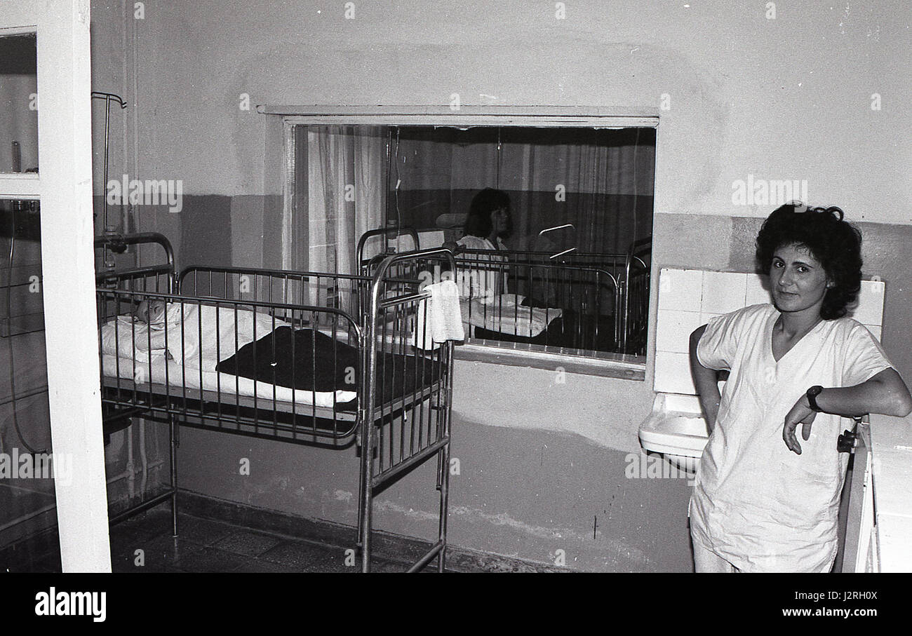 NURSE TALKING A PHOTO IN A ROOM - BABY LAYING IN A CRIB Stock Photo - Alamy