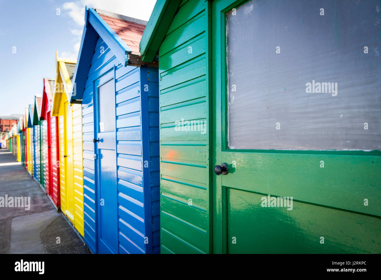 Row of brightly coloured wooden beach huts along the West Cliff ...