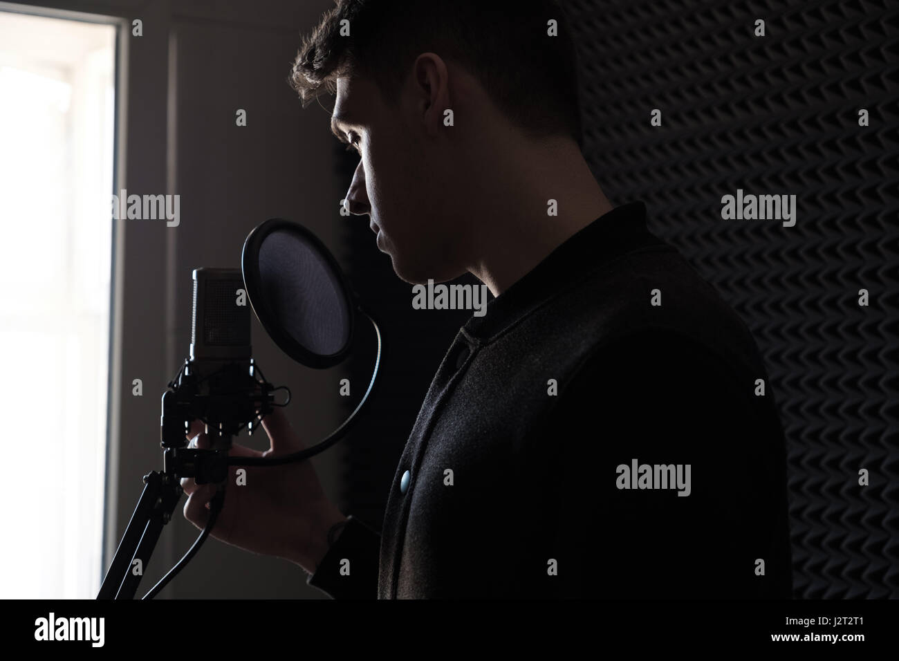 A guy holding a microphone standing on a counter in front of him , a ...
