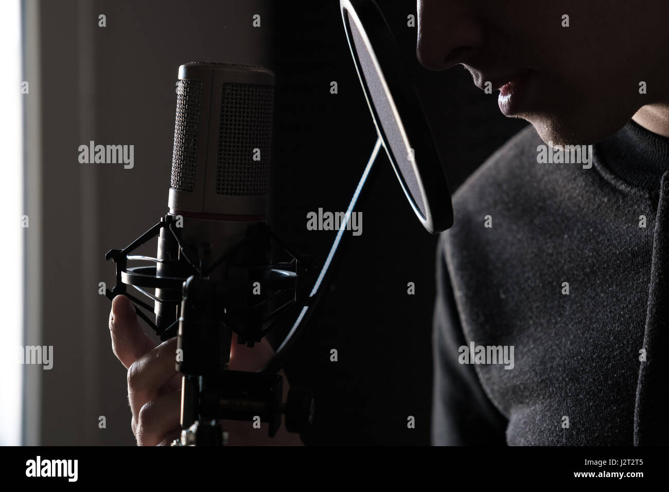 Closeup of lips and hands on a microphone of a young man standing in ...