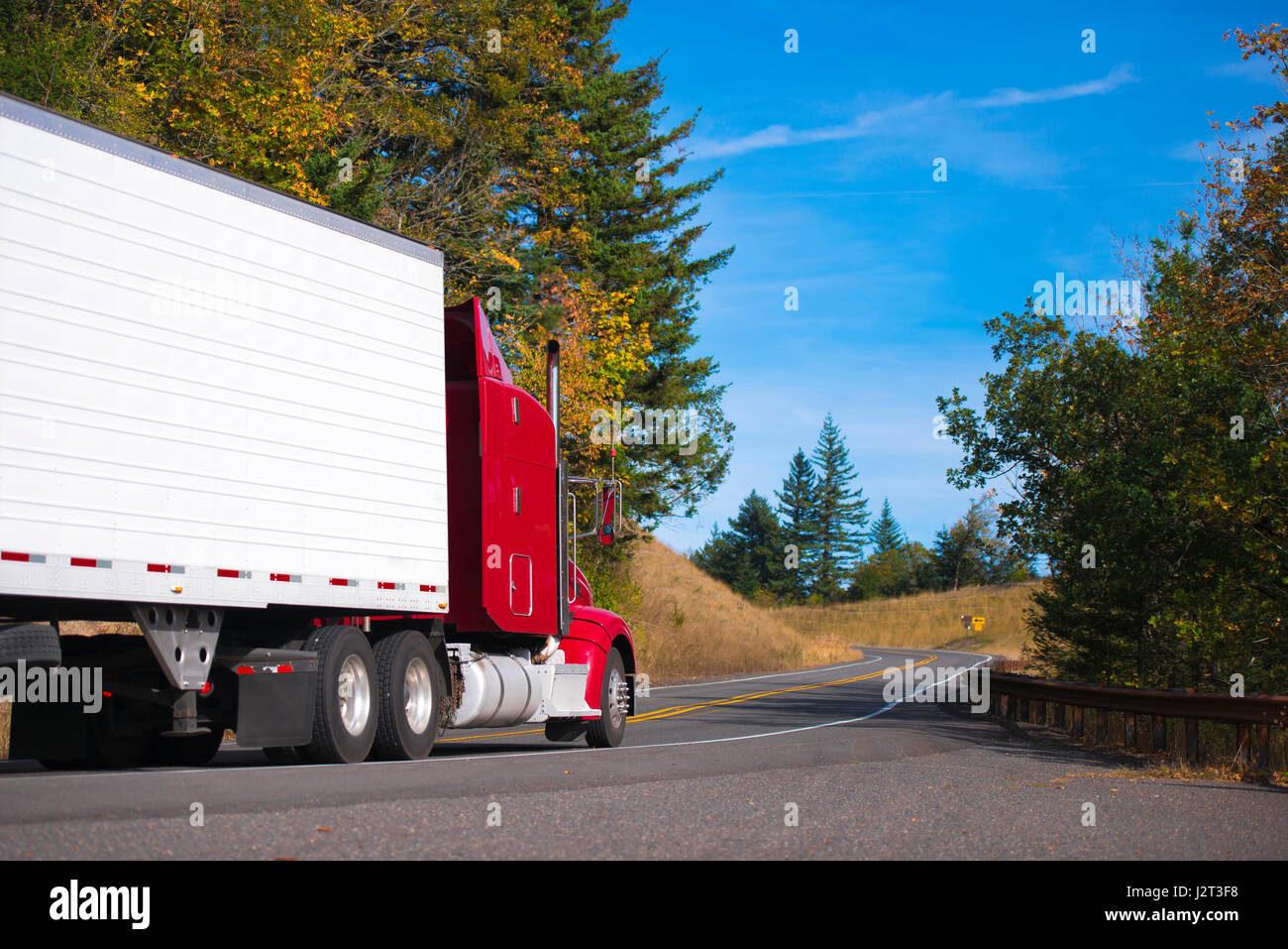 Classic red big rig long haul semi truck transporting cargo in refer ...