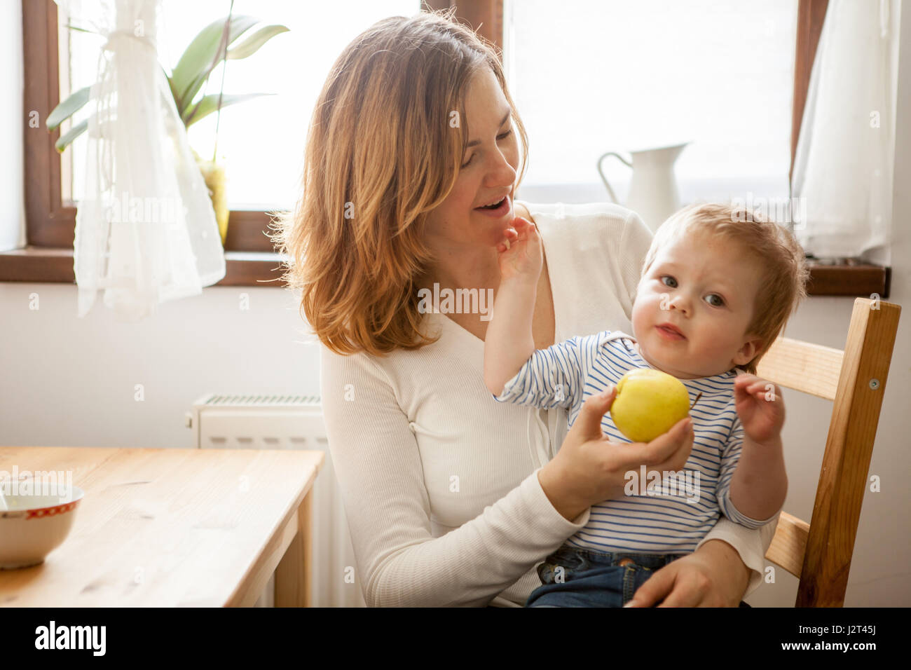 Mother trying to feed an apple to baby boy Stock Photo - Alamy