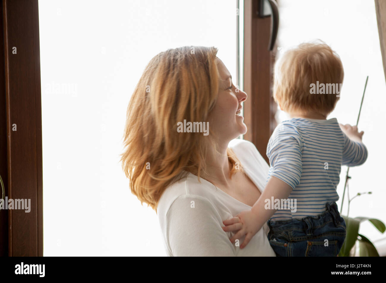 Mother with her baby boy looking at the window Stock Photo - Alamy
