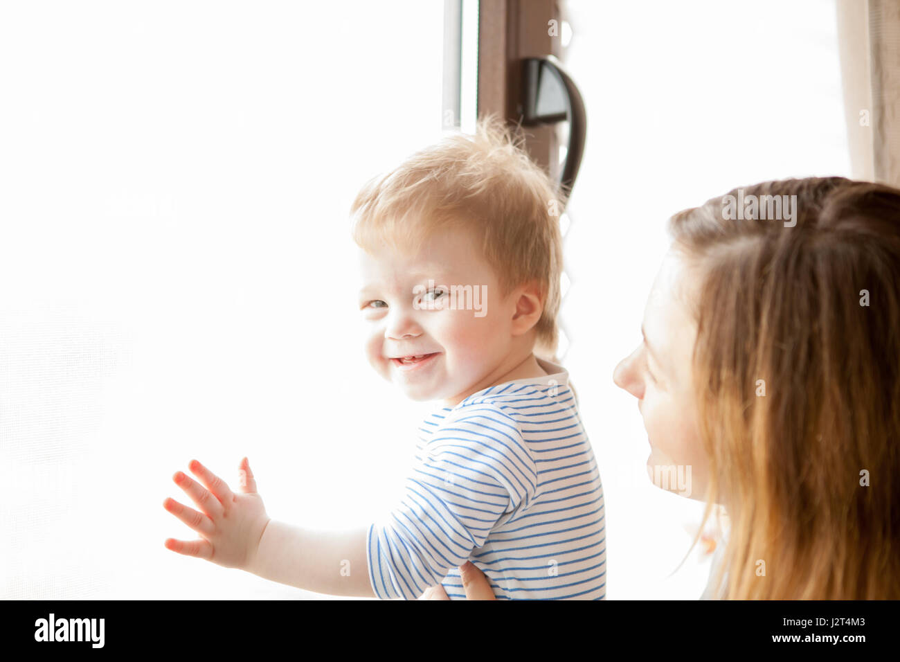 Mother with her baby boy looking at the window Stock Photo - Alamy