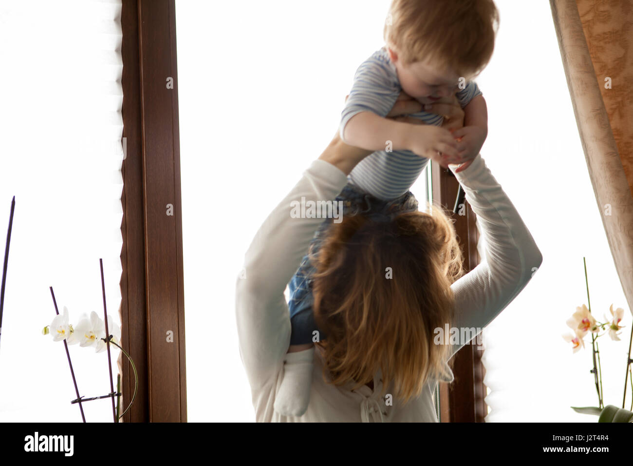 Mother with her baby boy looking at the window Stock Photo - Alamy