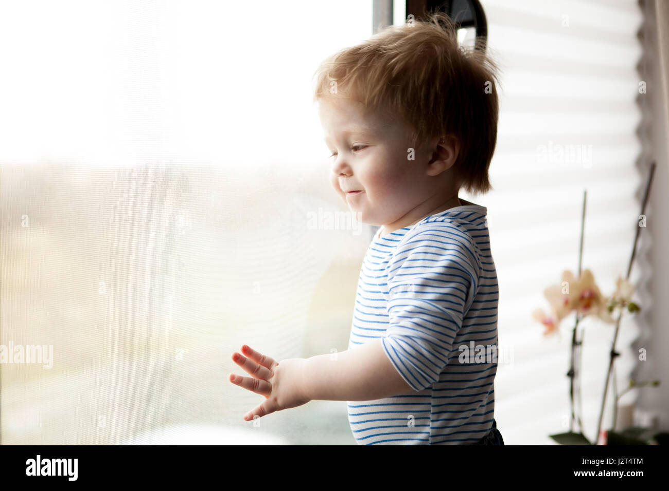 Cute little kid looking through the window Stock Photo - Alamy