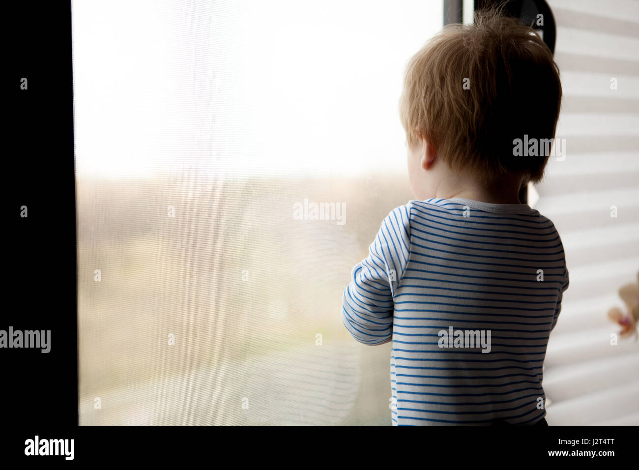 Cute little kid looking through the window Stock Photo - Alamy