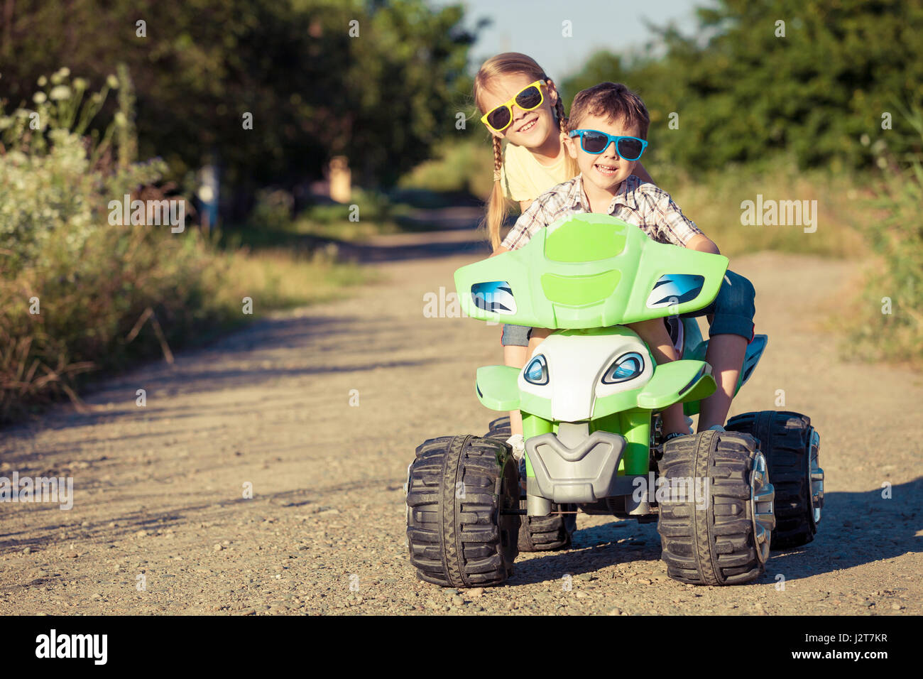 Happy little children playing on road at the day time. They driving on ...