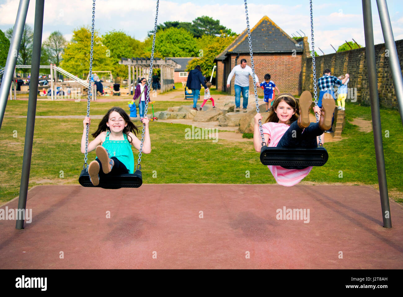 Horizontal portrait of two girls on swings at a park Stock Photo - Alamy