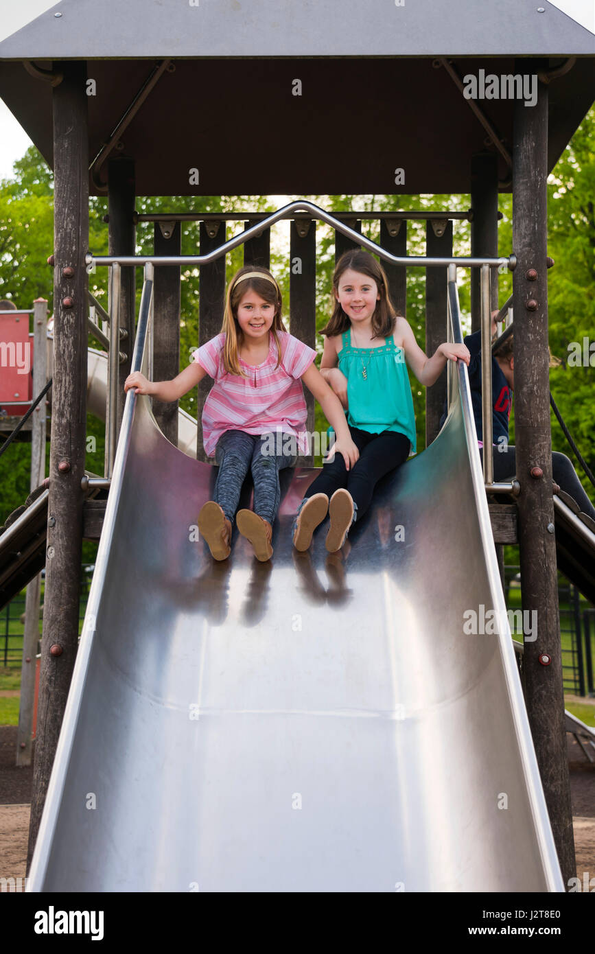 Vertical Portrait Of Two Girls Sliding Down A Slide Together In The