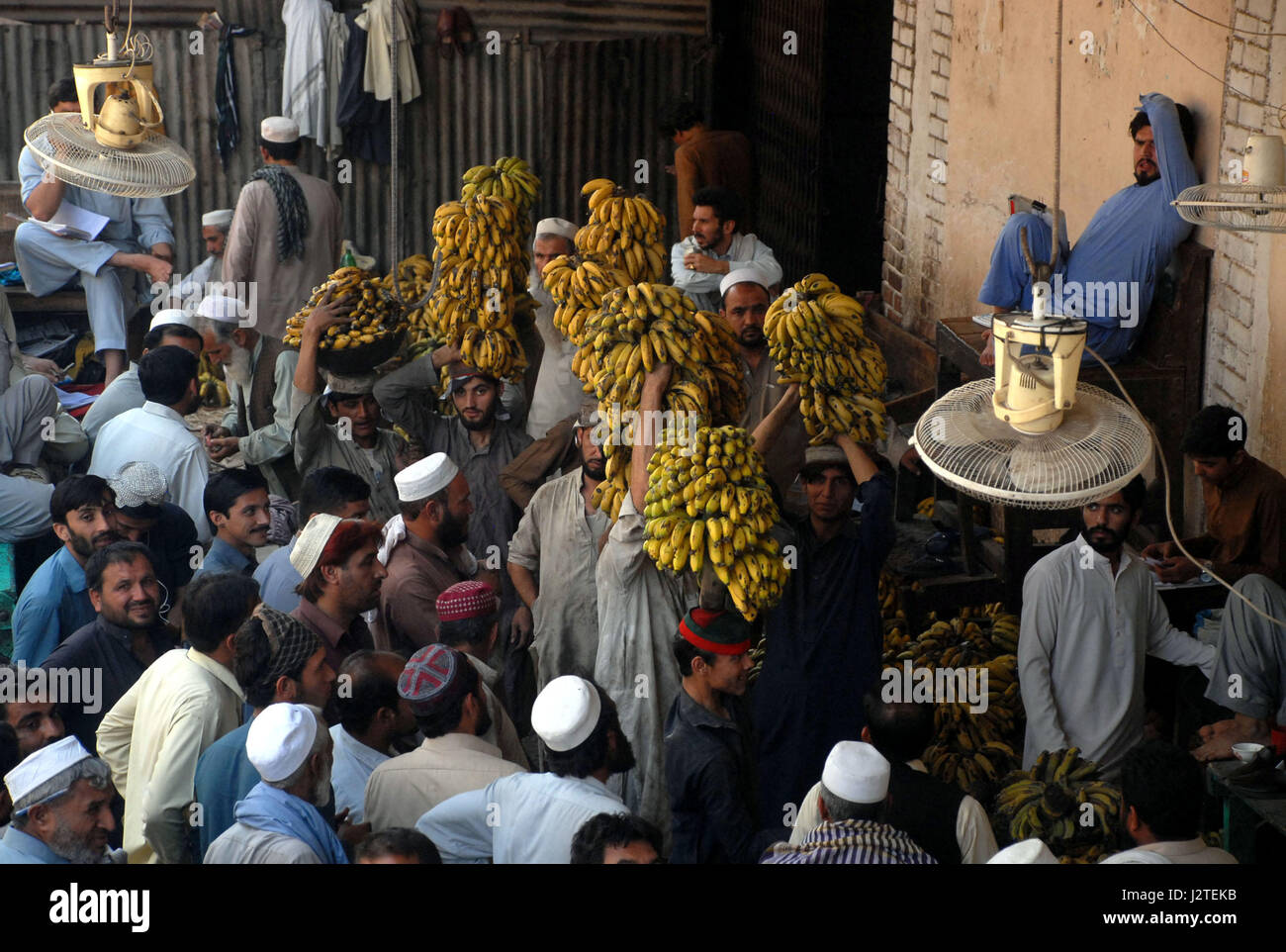 Peshawar. 1st May, 2017. Pakistani labourers carry piles of bananas at ...