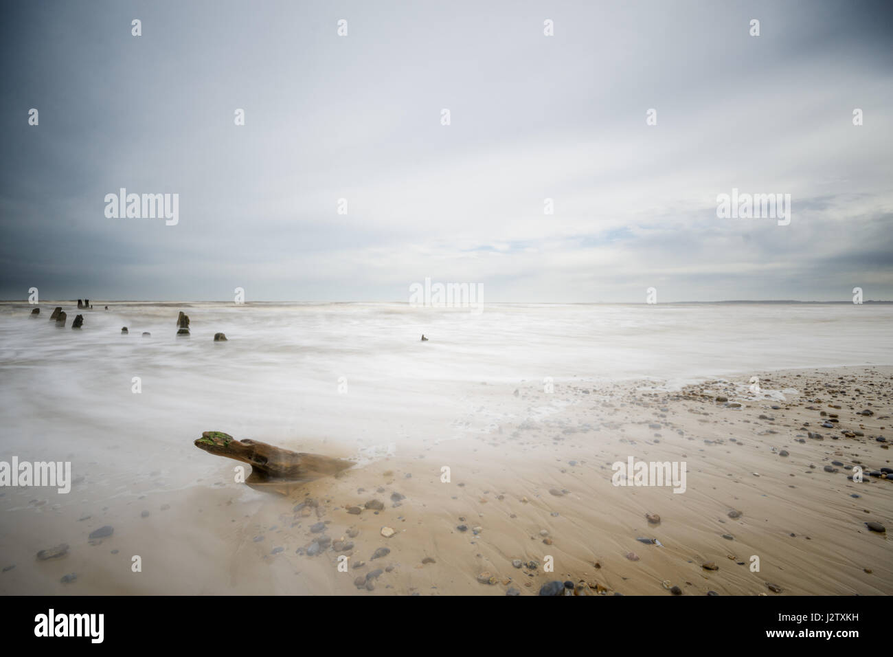 Walberswick on the Suffolk Coast. Posts washing in the sea on the sandy ...