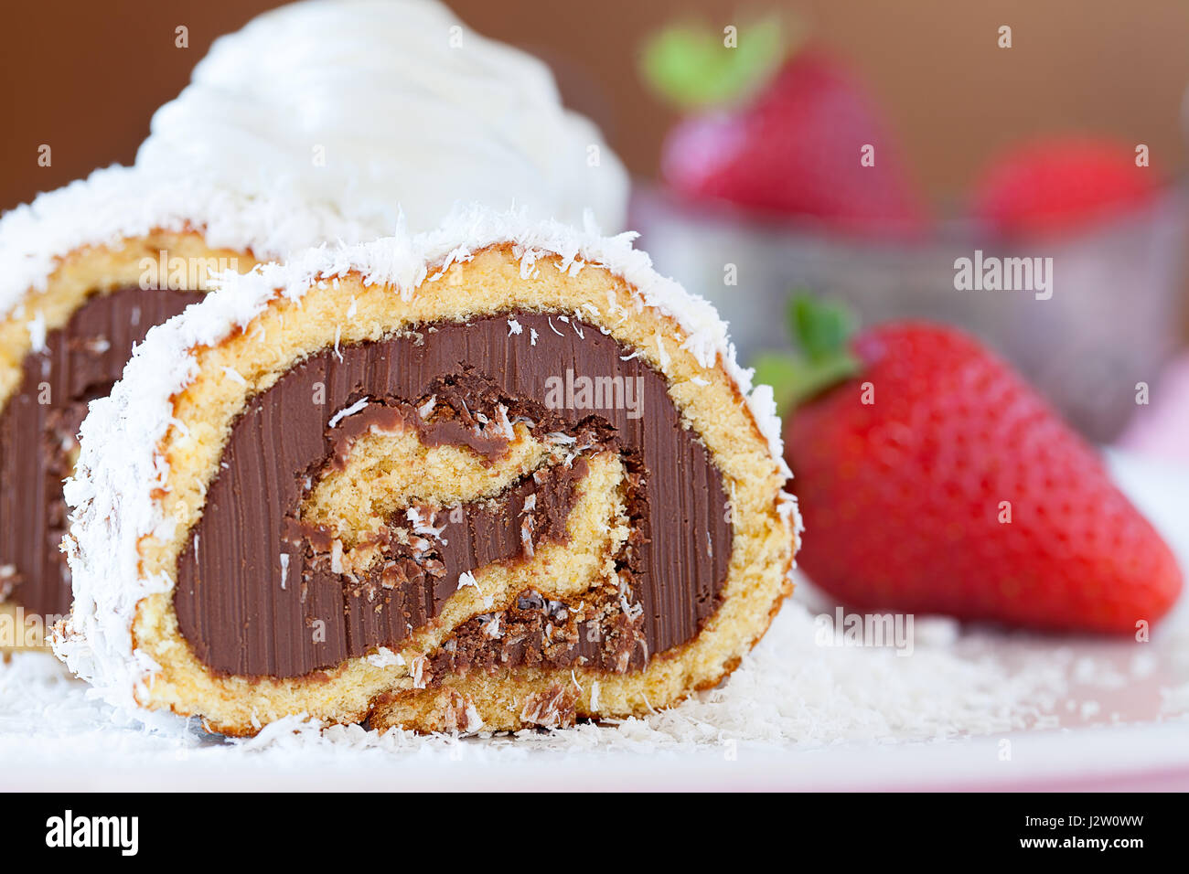 Slice of chocolate coconut cake roll decorated with ehipped cream and ...