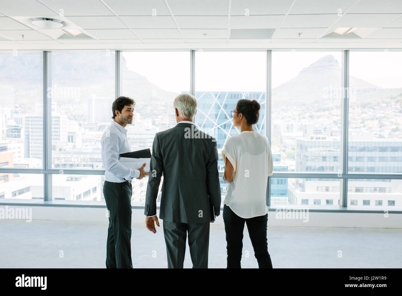 Business people and real estate agent discussing at empty office space ...
