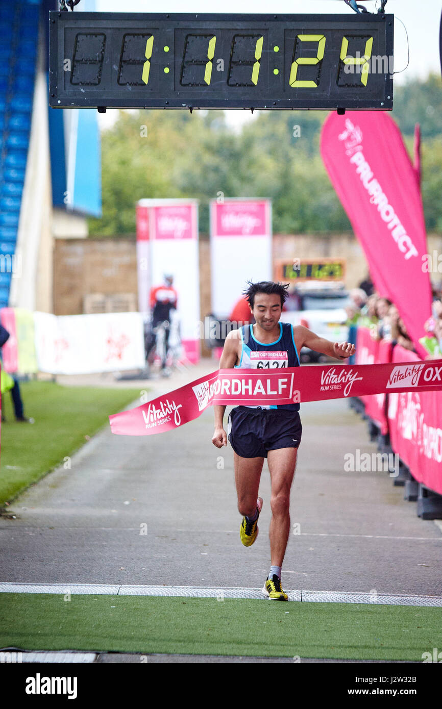A runner crosses the finish line to win the 2014 Oxford Half Marathon ...