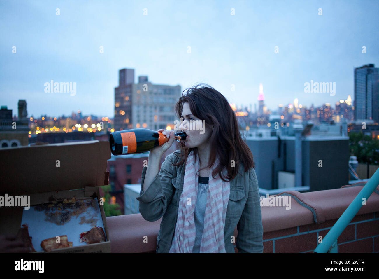 Young woman hanging out on a building rooftop Stock Photo - Alamy