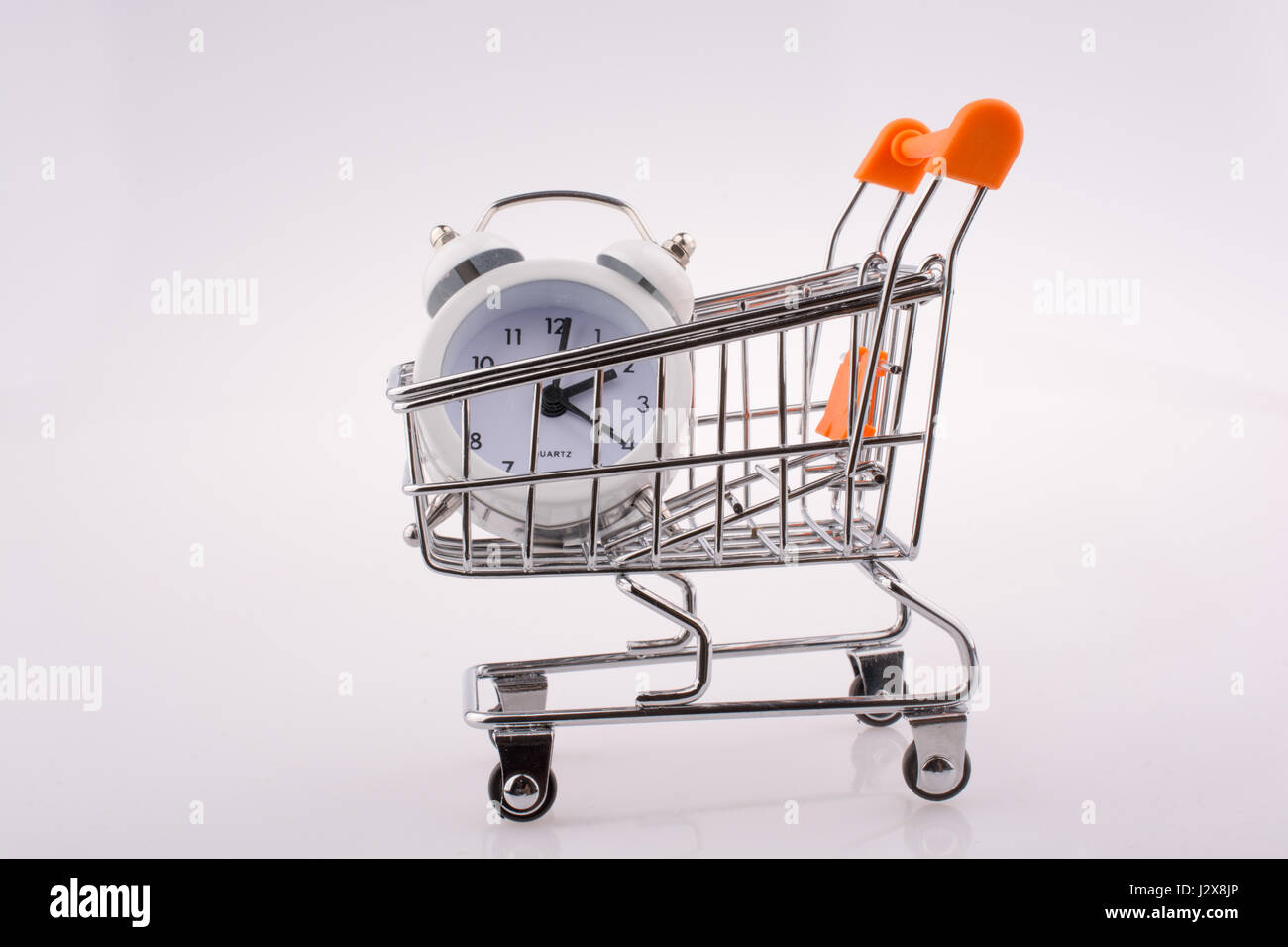 Alarm clock in a shopping trolley on white background Stock Photo - Alamy