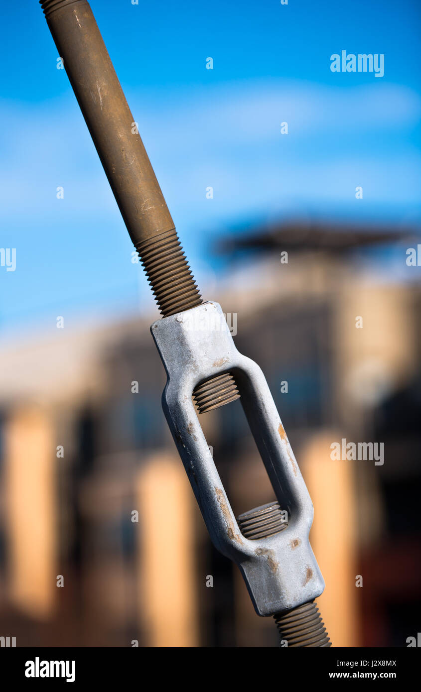 Metal coupling on the threaded screed on blurred background buildings ...