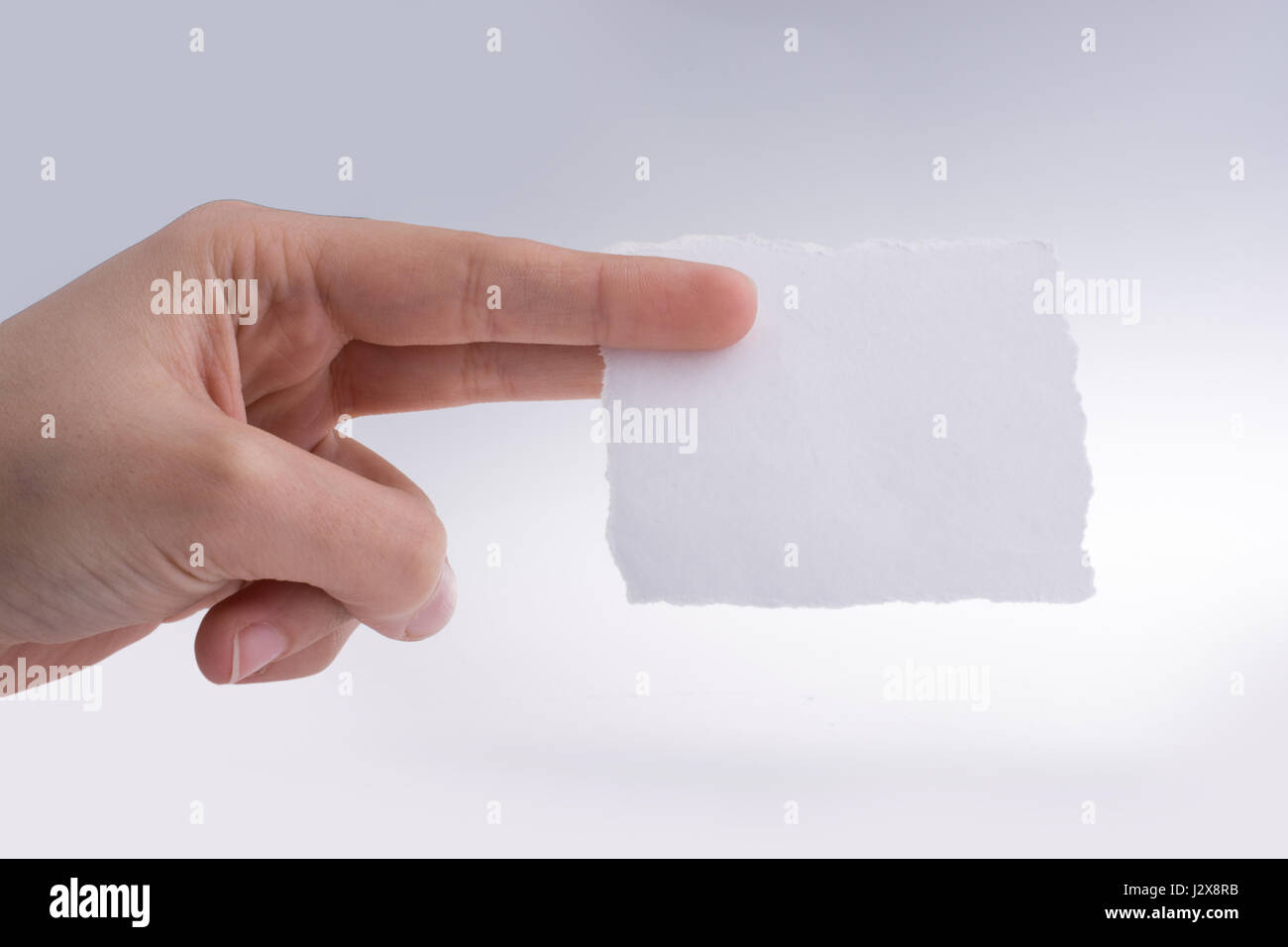 Hand holding a a piece of torn paper on a white background Stock Photo ...