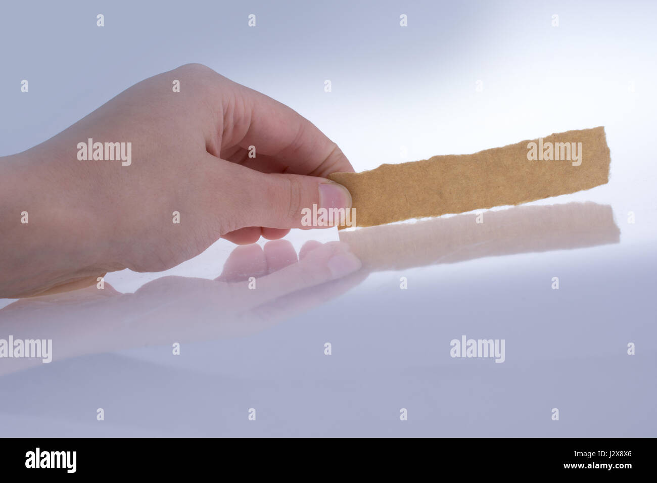 Hand holding a a piece of torn paper on a white background Stock Photo ...