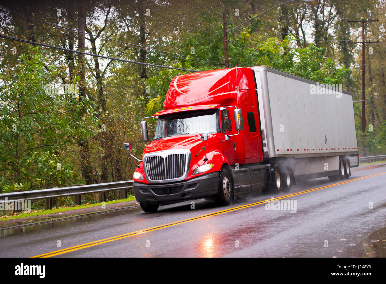 Big red semi truck shiny and wet from the rain with the reflection of ...